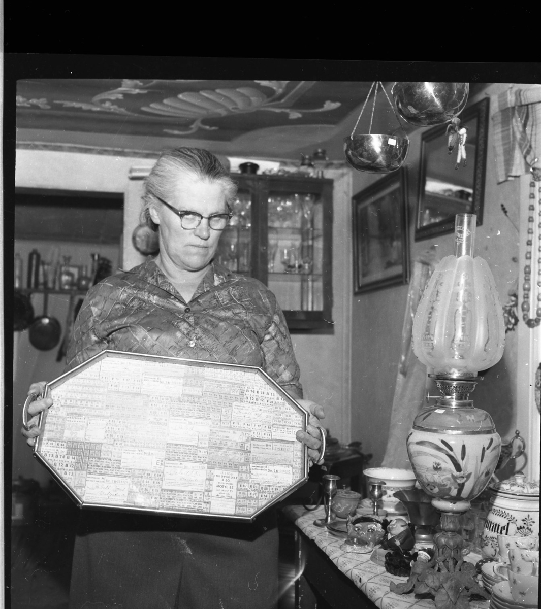 En kvinna visar upp en bricka. Brickan har motivet av ...