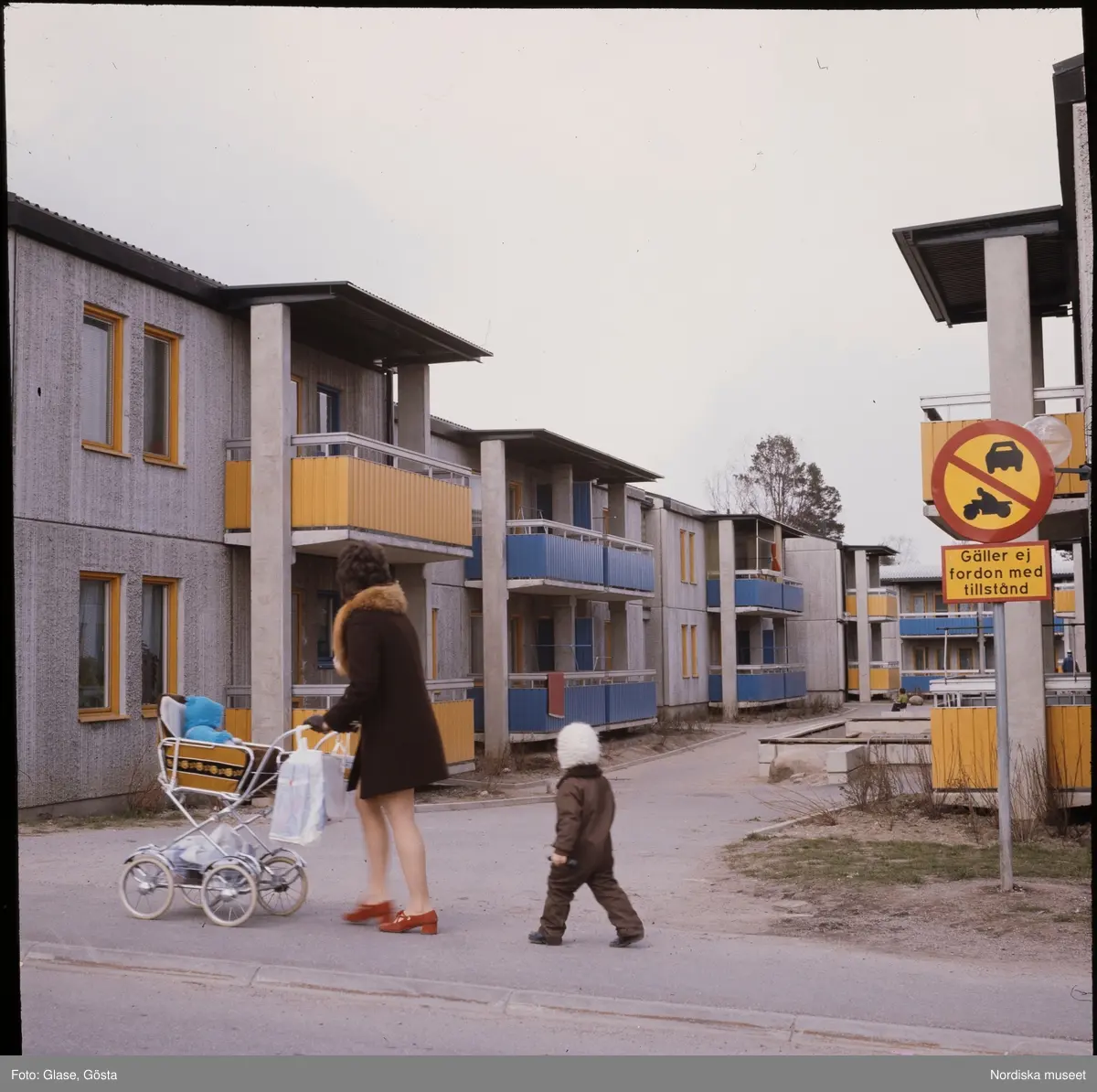 Orminge. En mamma med två barn, det ena i barnvagn, passerar på gatan i ...