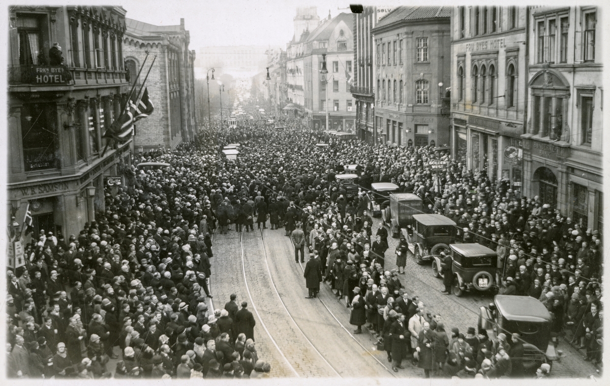 Karl Johans gate sett mot Stortinget med parkerte biler og tilskuer ...