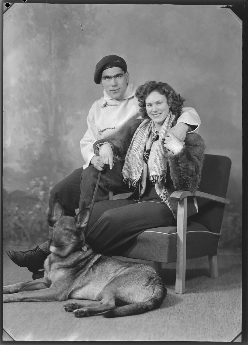 Portrett av et par som holder rundt hverandre med en hund i halsbånd ...