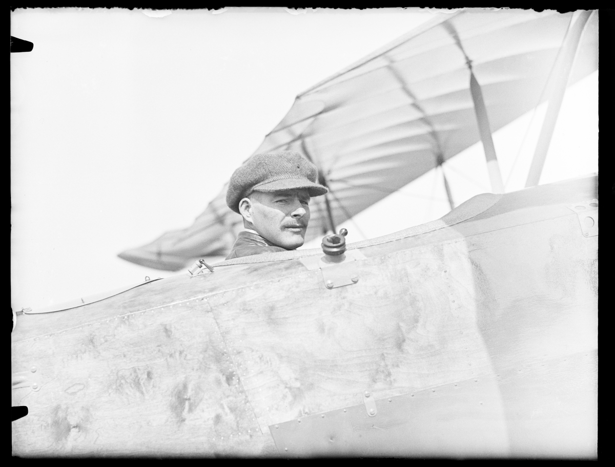 Porträttfoto av flygare iförd keps i förarsits på flygplan tillhörande ...