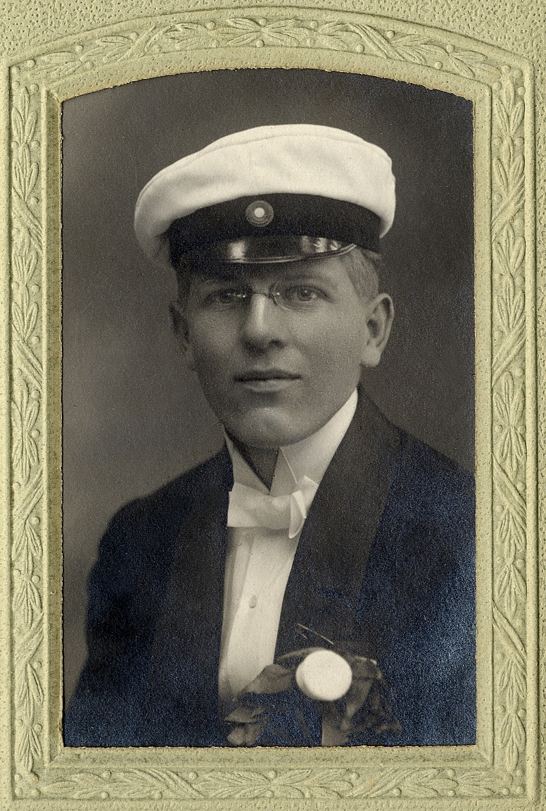 En okänd man i frack med stärkkrage och studentmössa. På kavajslaget ...