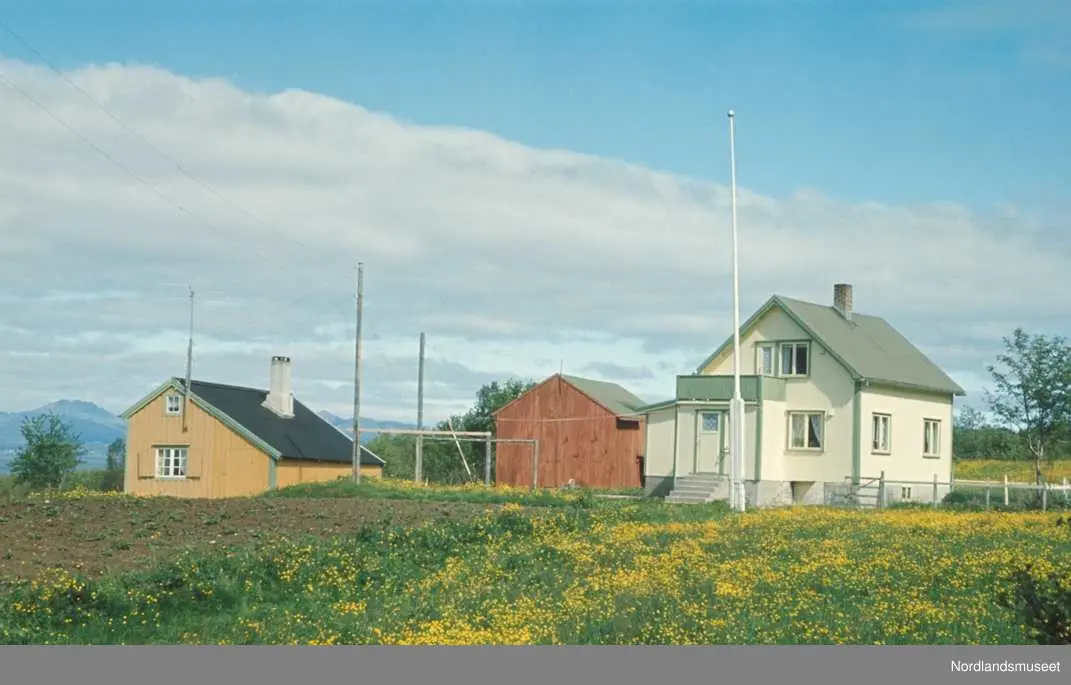 Husmannsstue. Hvitt hus med bislag, trappe og balkon, en flaggstang ...