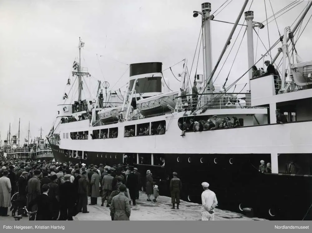 Nordgående hurtigrute. Dampbåt ligger ved kai. Mange mennesker samlet ...