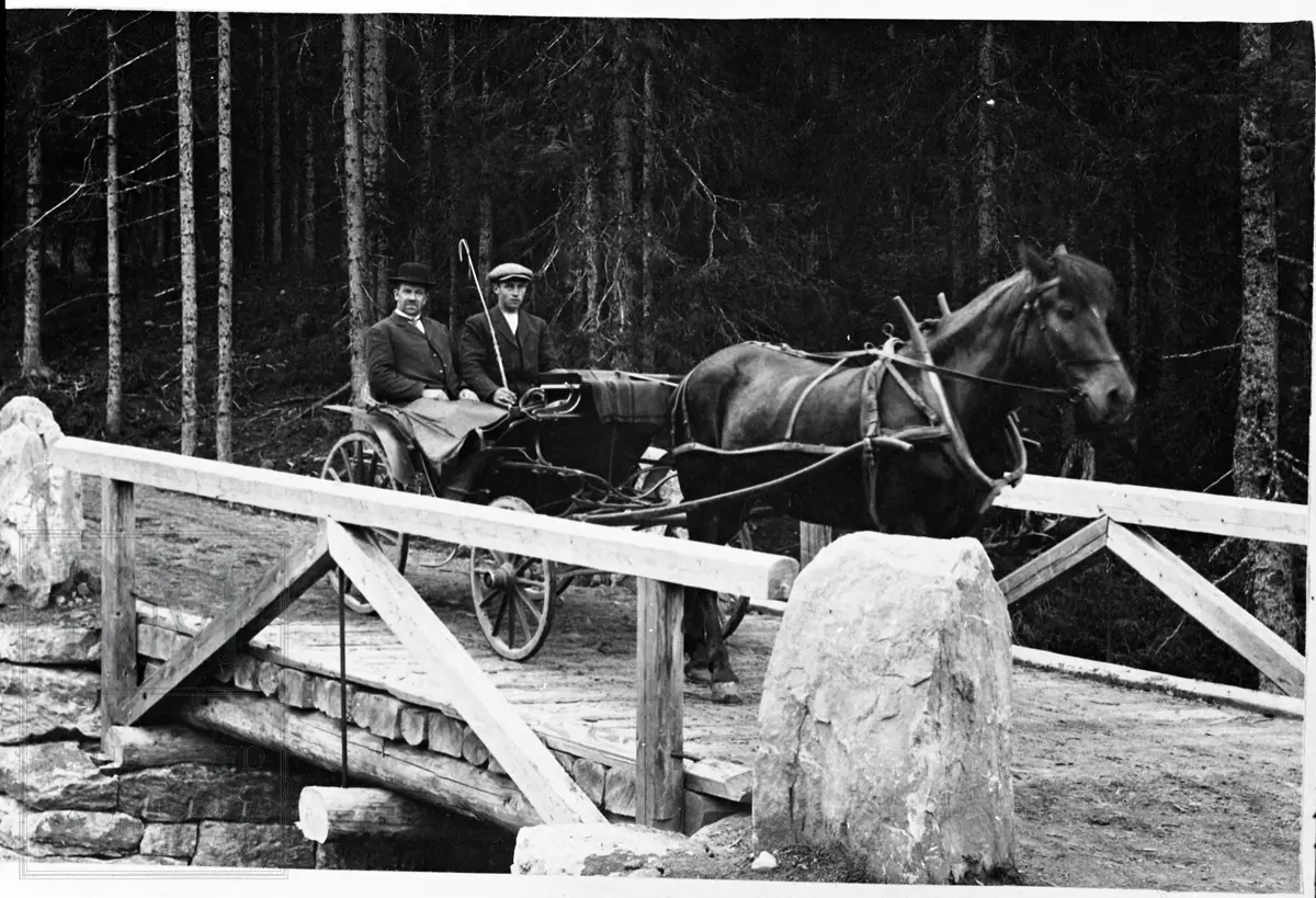 Inge Iversen og Guvald Felberg kjører over ei bru med hest og vogn ...